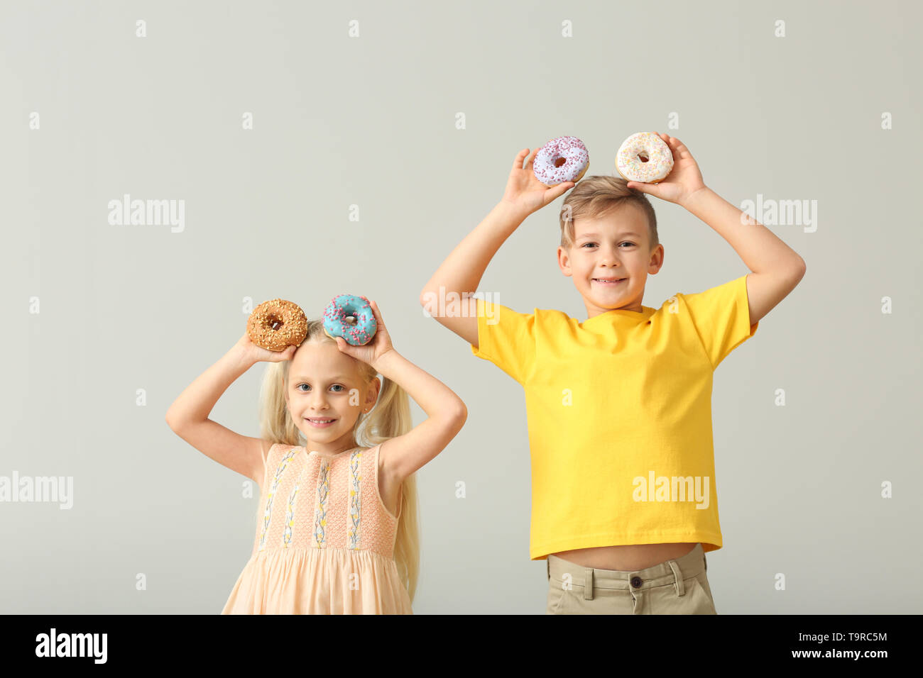 Cute little children with donuts on light background Stock Photo - Alamy
