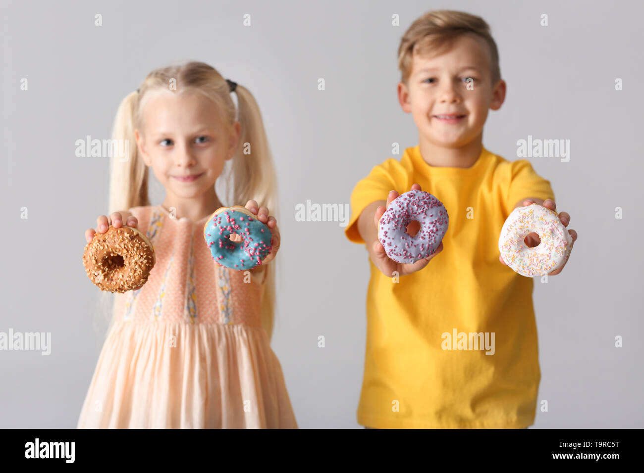 Cute little children with donuts on light background Stock Photo - Alamy