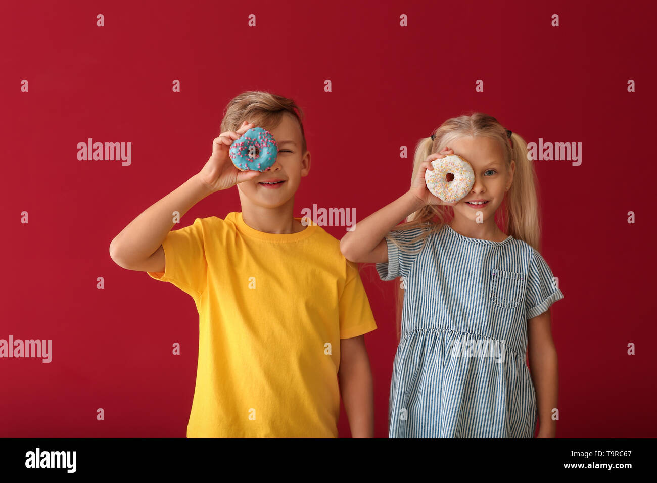 Cute little children with donuts on color background Stock Photo - Alamy