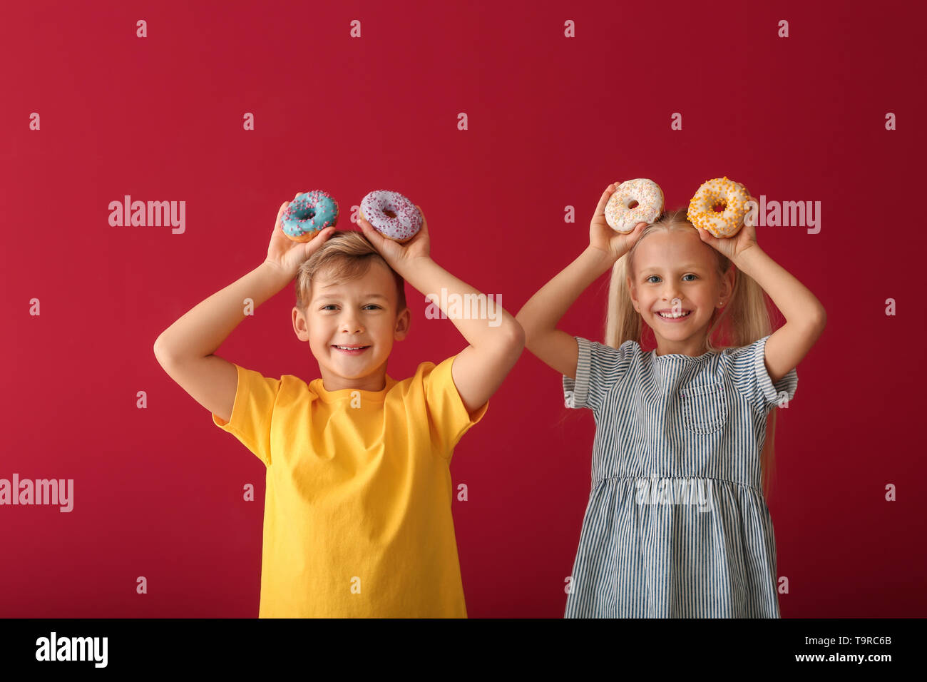 Cute little children with donuts on color background Stock Photo - Alamy