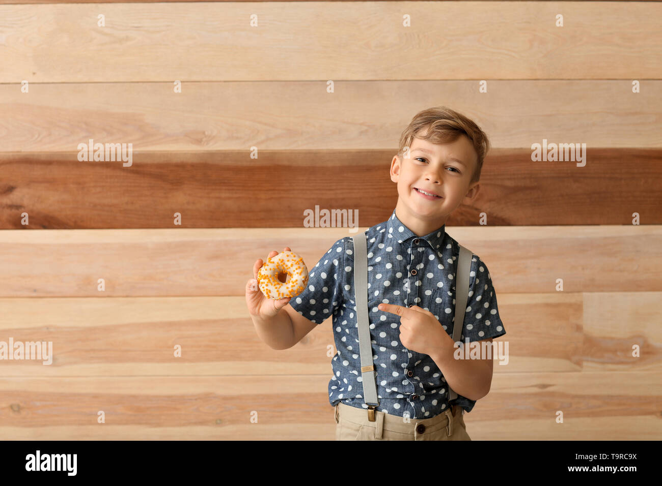 Cute little boy with donut on wooden background Stock Photo - Alamy