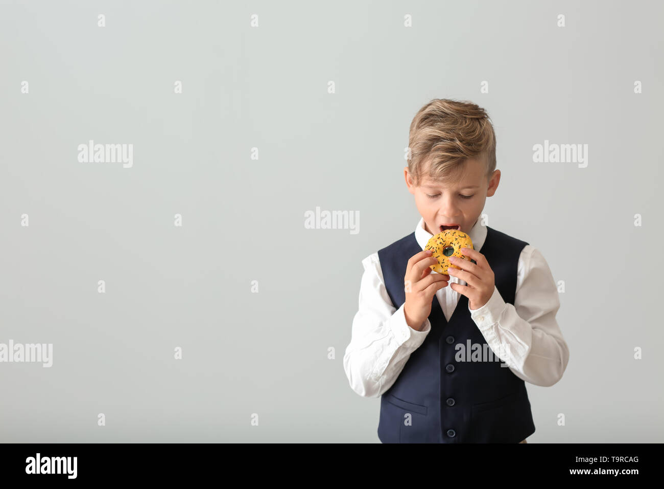Cute little boy with donut on light background Stock Photo - Alamy