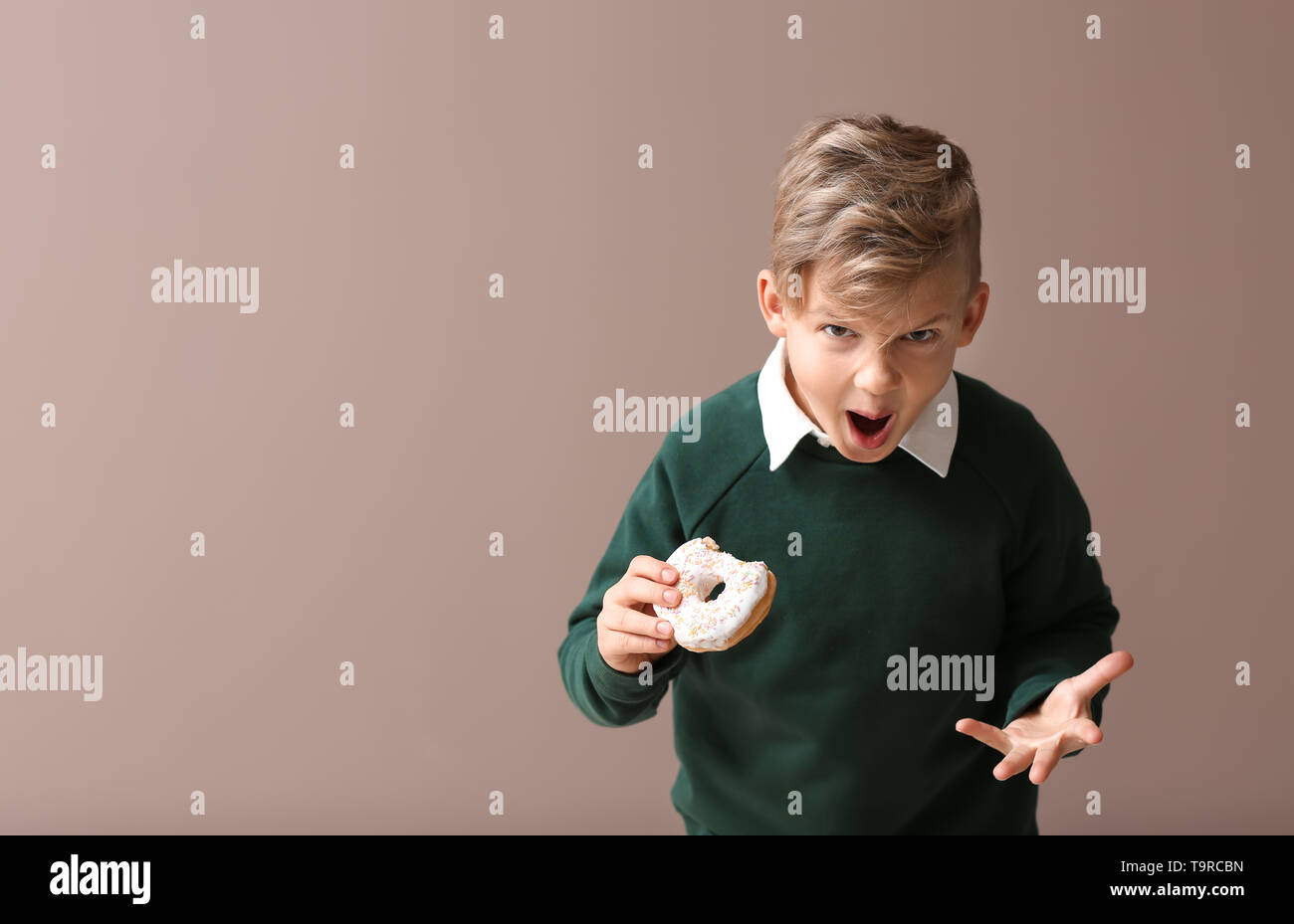 Angry little boy with donut on color background Stock Photo - Alamy