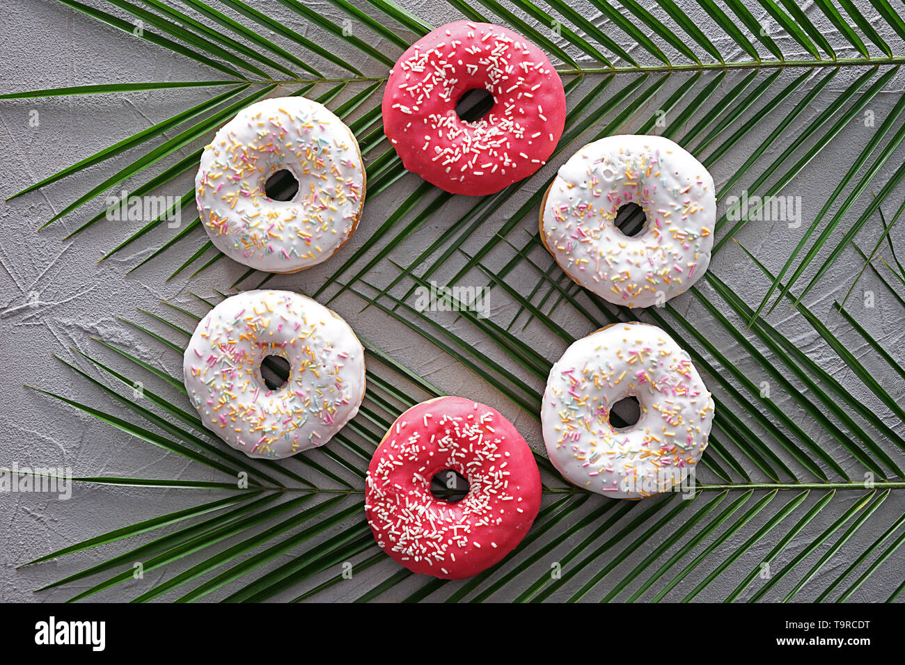 Tasty donuts and palm leaves on grey background Stock Photo - Alamy