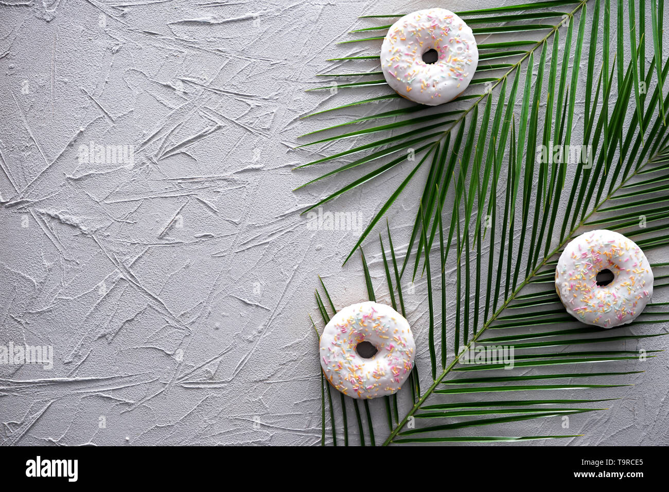 Tasty donuts and palm leaves on grey background Stock Photo - Alamy