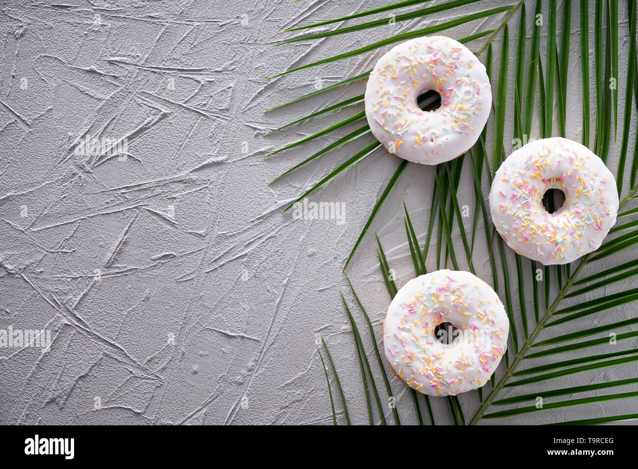 Tasty donuts and palm leaves on grey background Stock Photo - Alamy