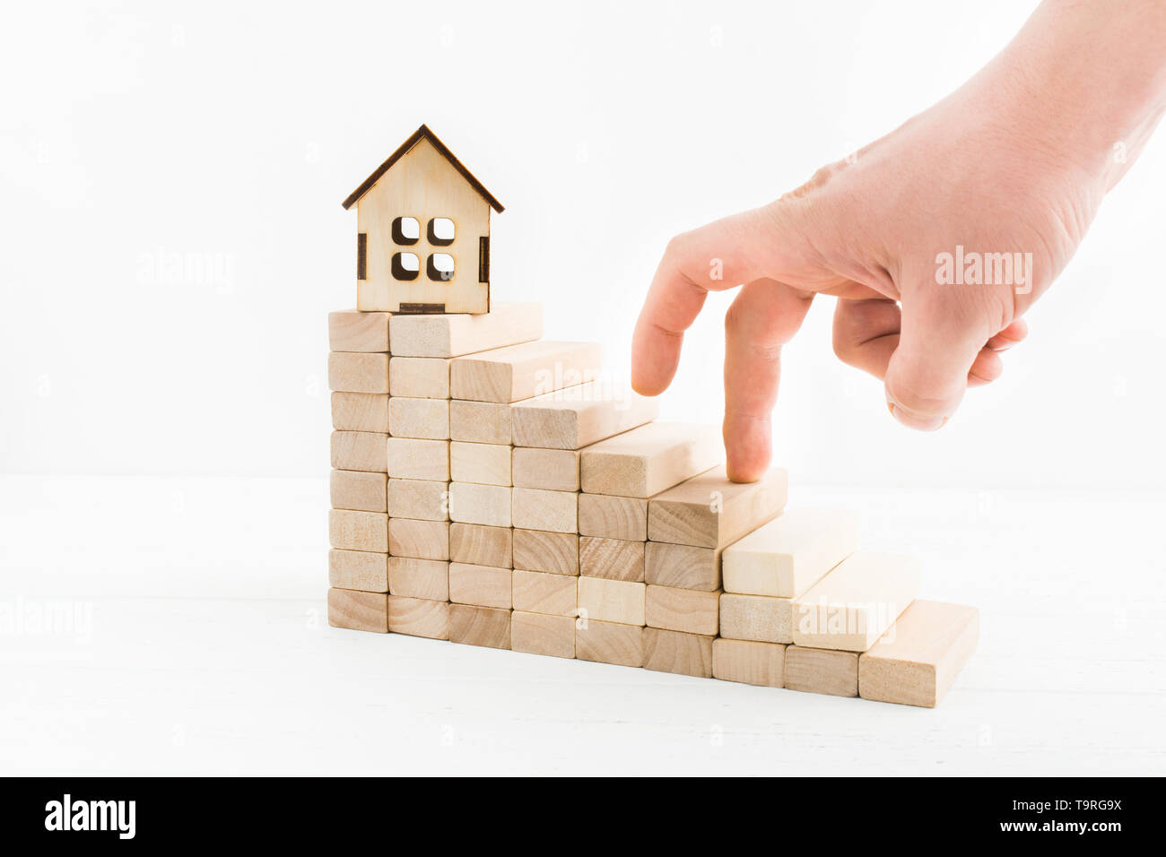 Wooden stairs of blocks with wooden house and man hand going up to ...