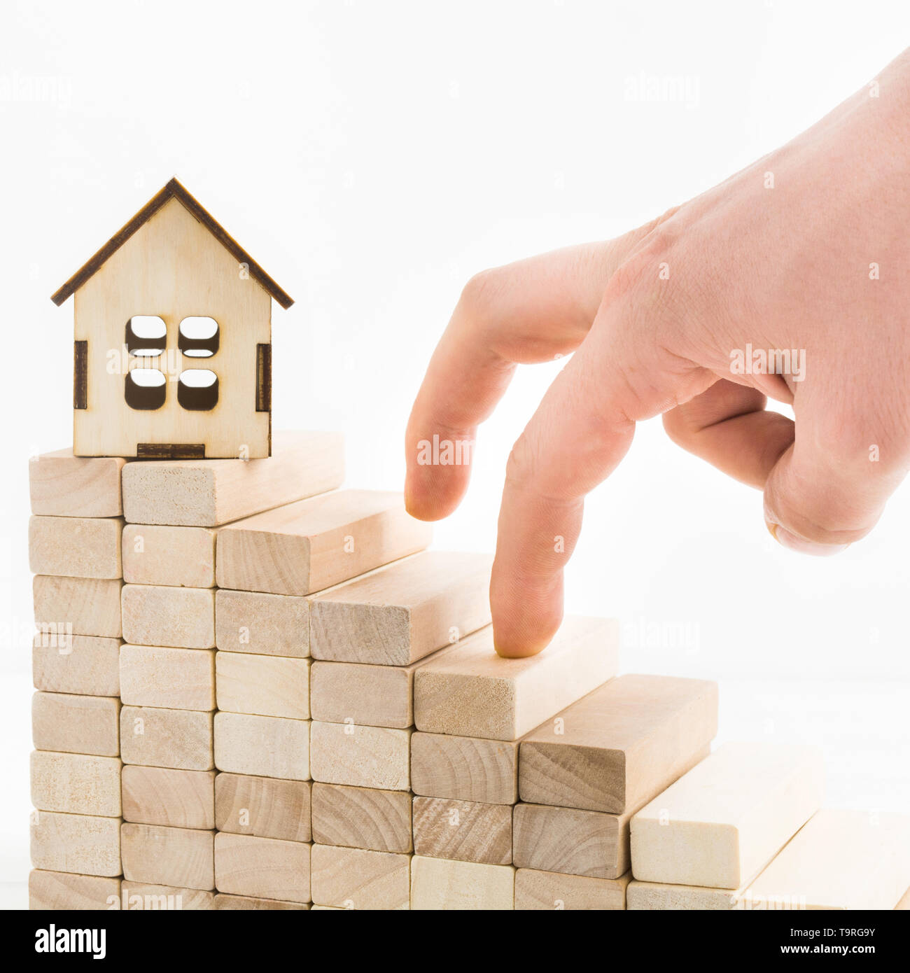 Male hand going upstairs with wooden house. Architecture investment ...