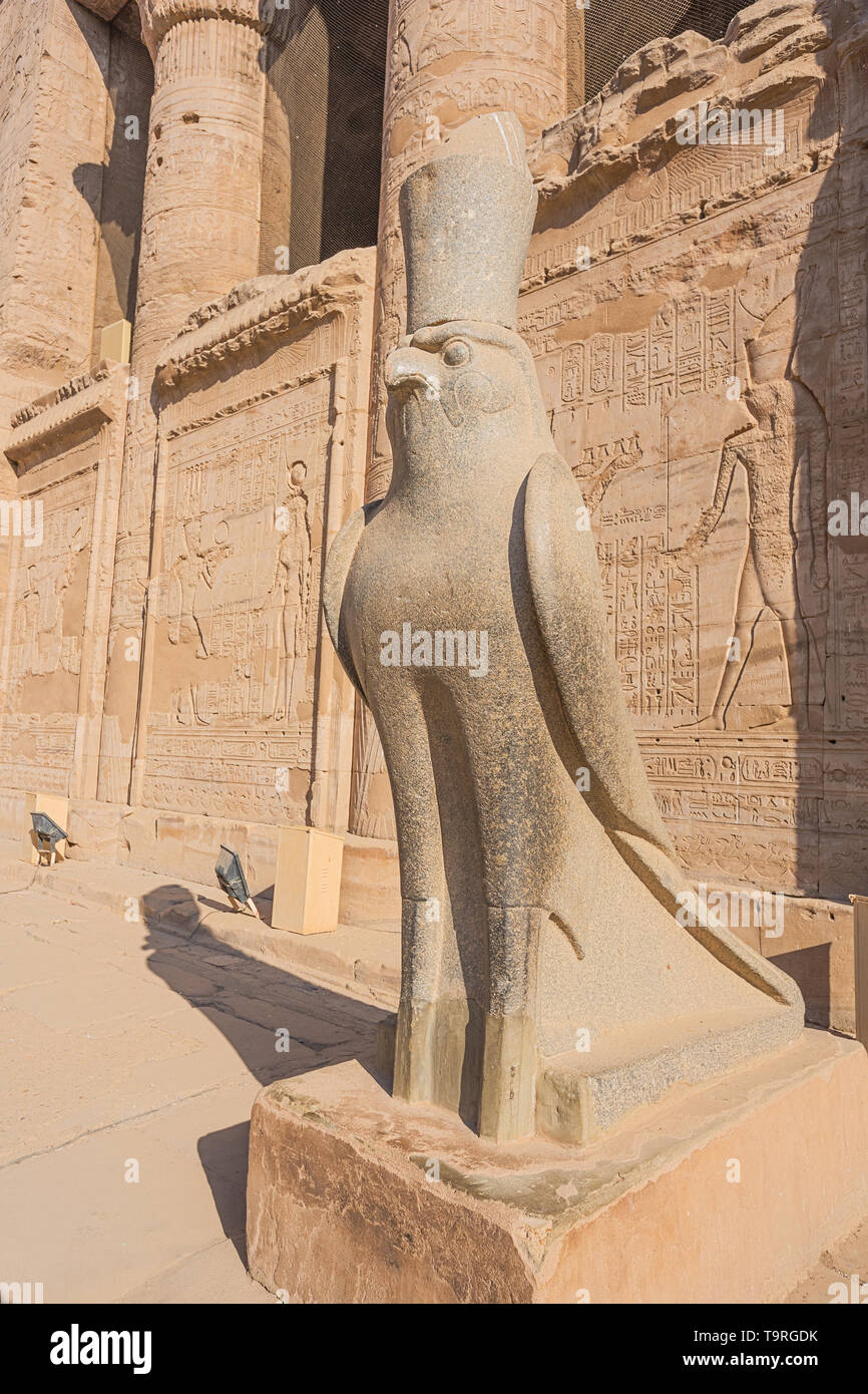 Standing next to the bird statue of Horus at the entrance of the temple ...