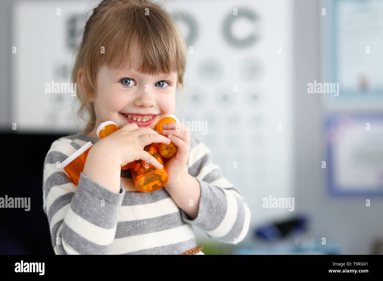 Cute smiling happy little girl grab pile of bottles with tablets at ...
