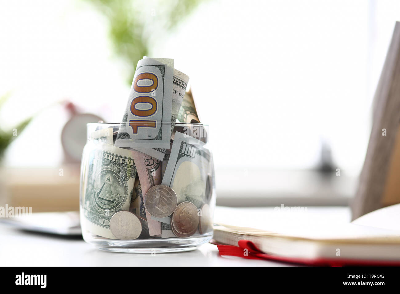 Big jar full of US notes and coins standing on empty worktable Stock ...