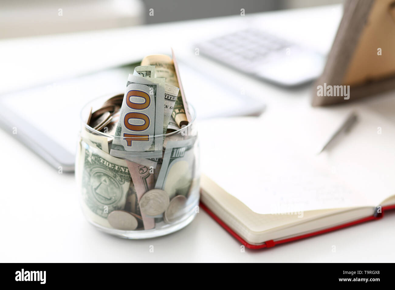 Big jar full of US notes and coins standing on empty worktable Stock ...