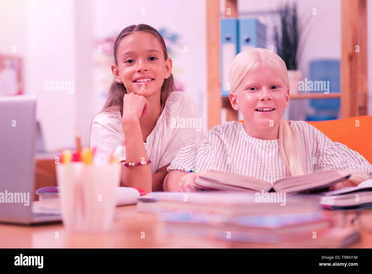 Two happy children sitting at the desk Stock Photo - Alamy
