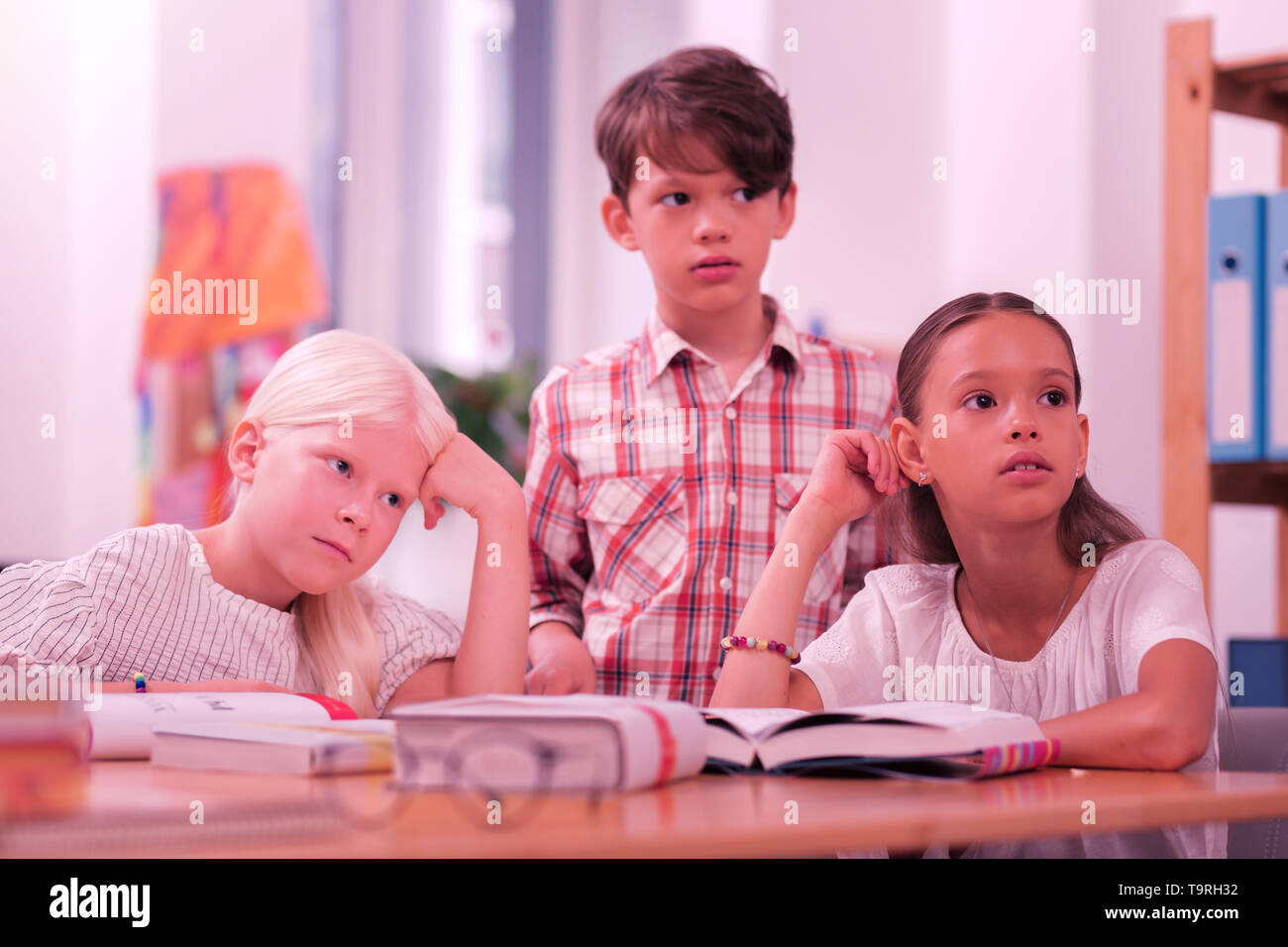 Three confused pupils listening to their teacher Stock Photo - Alamy