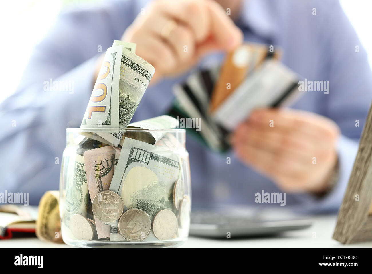 Big jar full of money stand at working table with male hand holding ...