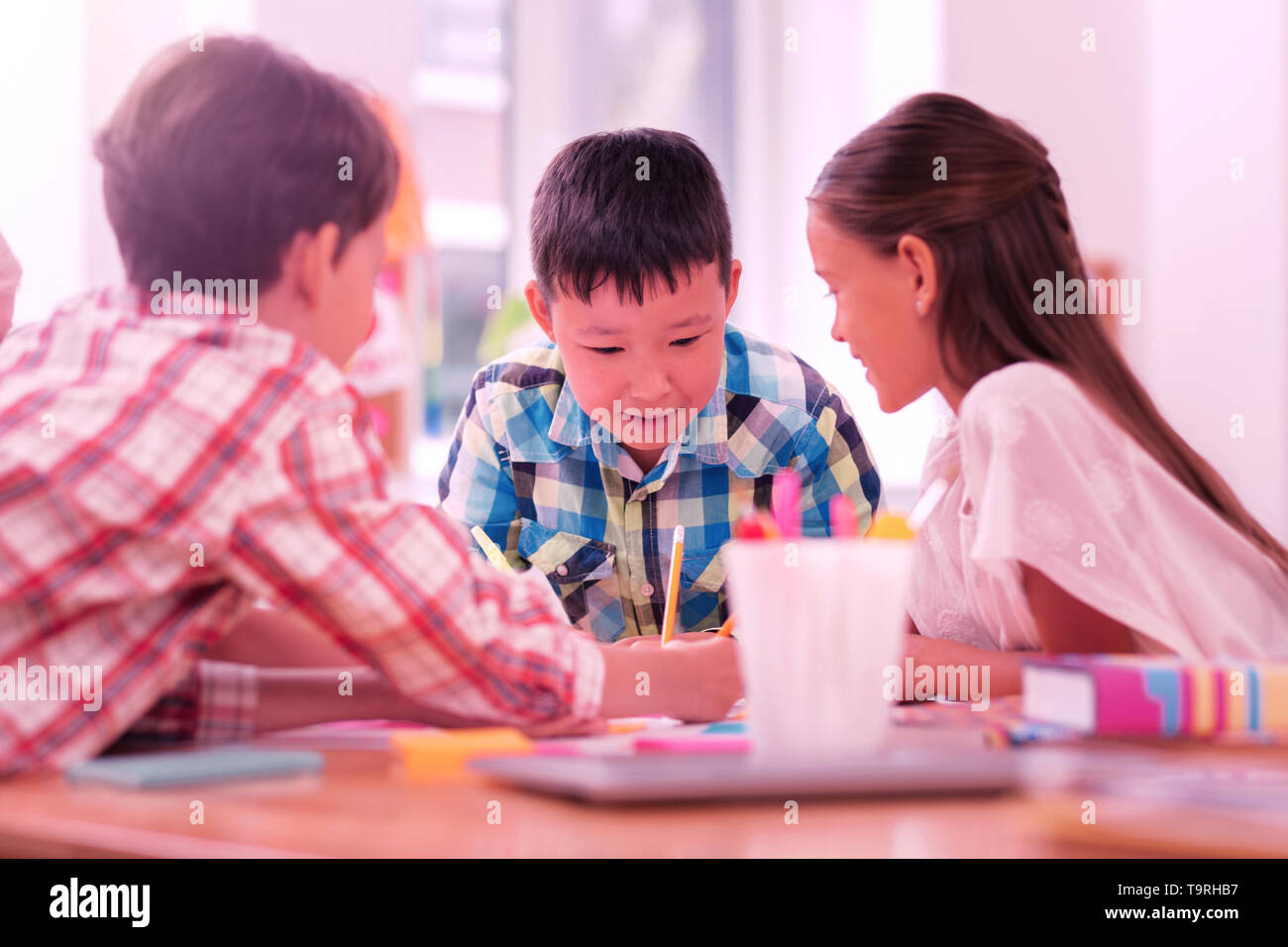 Three children drawing a school project together Stock Photo - Alamy