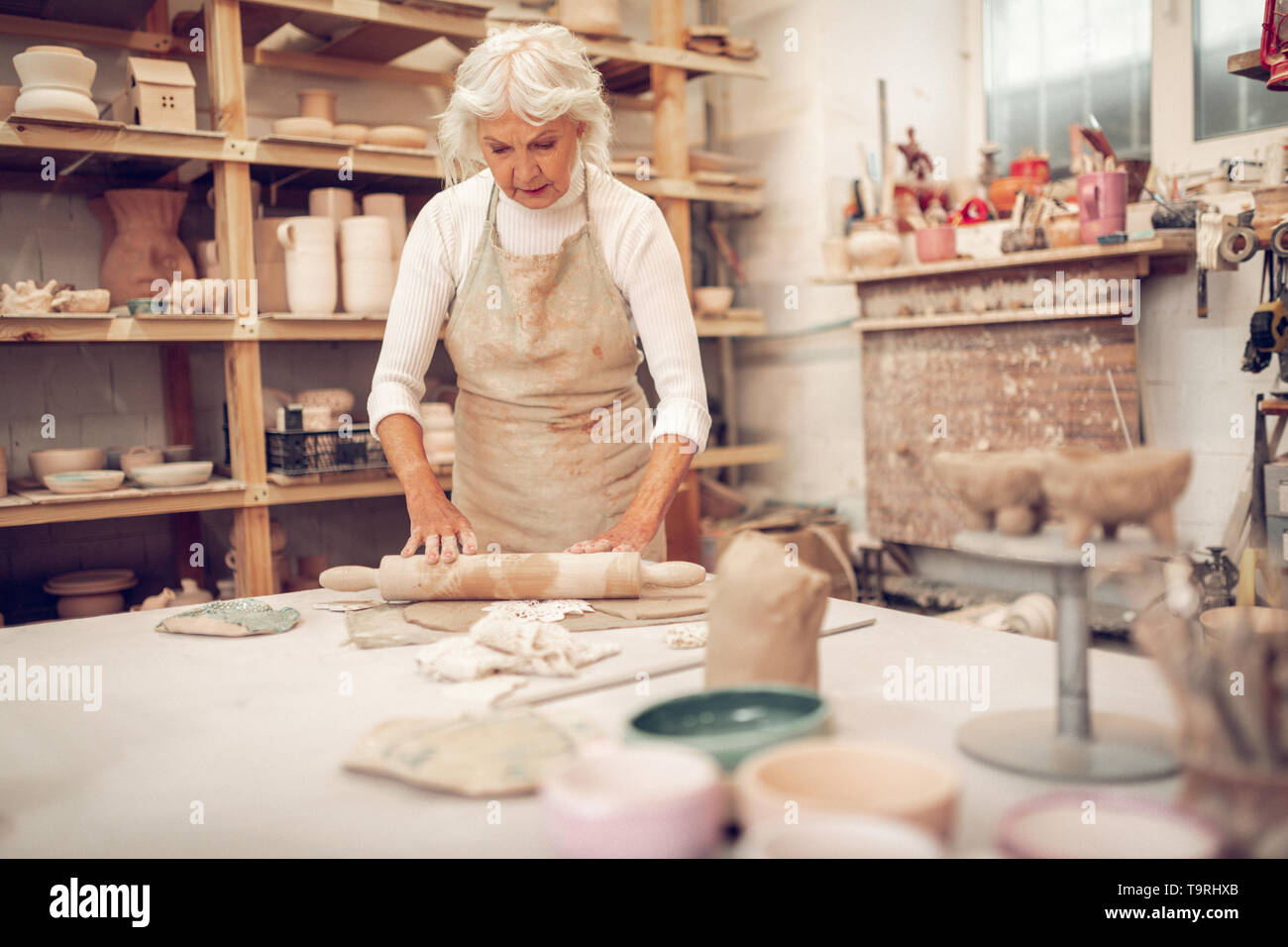 Nice hard working woman rolling out the clay piece Stock Photo - Alamy