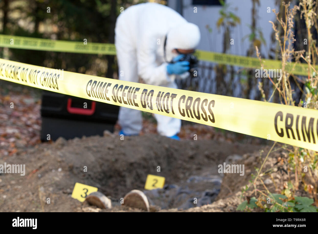 Forensic science specialist in white workwear taking photos of the ...