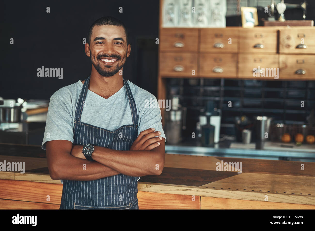 Young smiling barista posing near the counter at his cafe Stock Photo ...