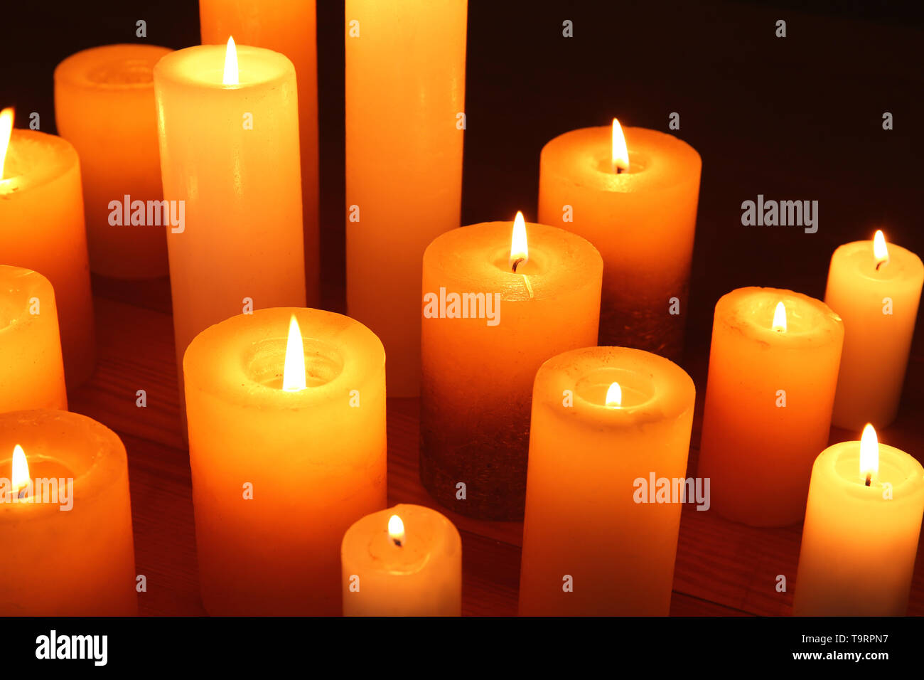 Many burning candles in darkness Stock Photo - Alamy
