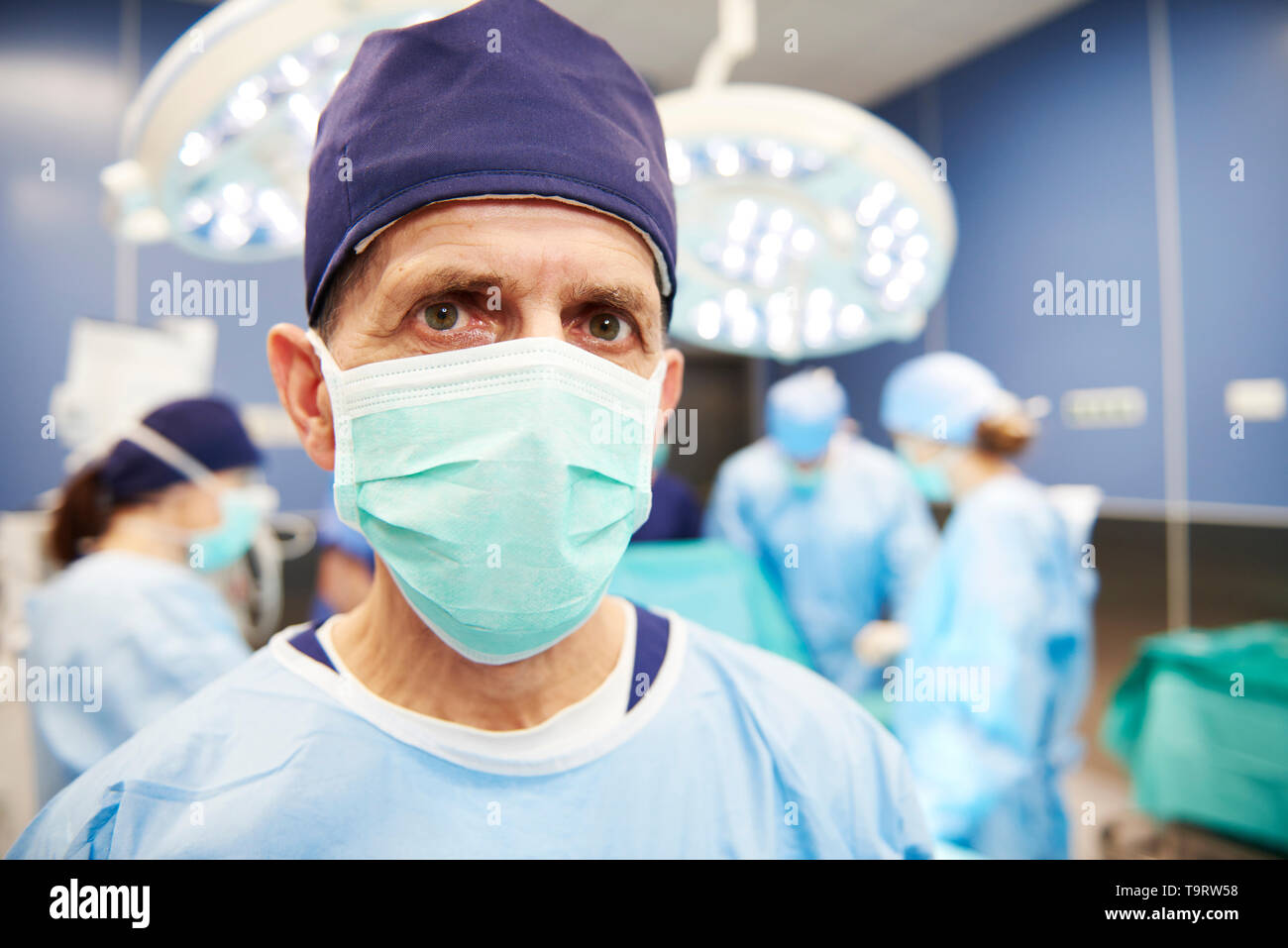 Portrait of senior surgeon with surgical cap and mask over gray ...