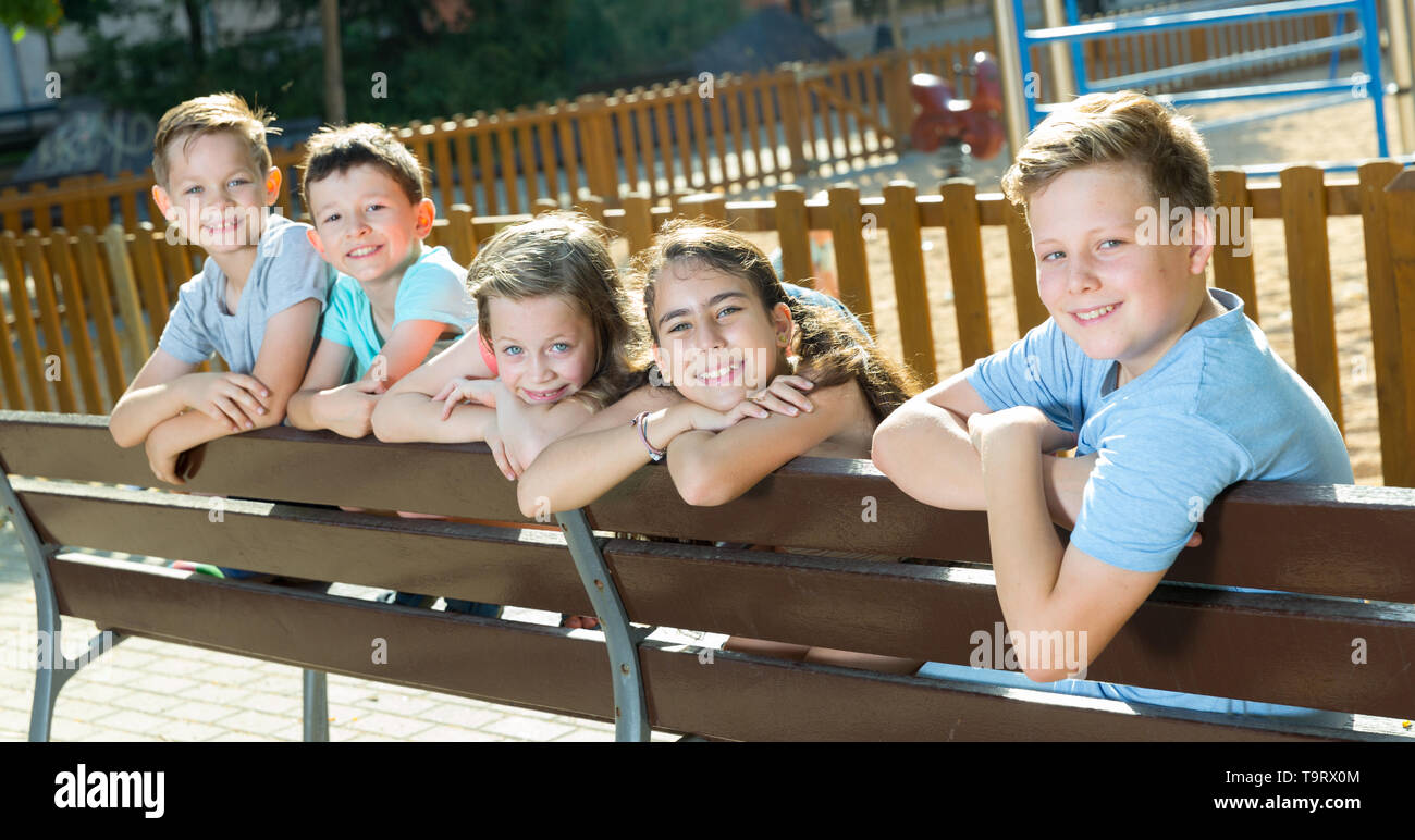 Five glad children sitting on a bench at the playground Stock Photo - Alamy