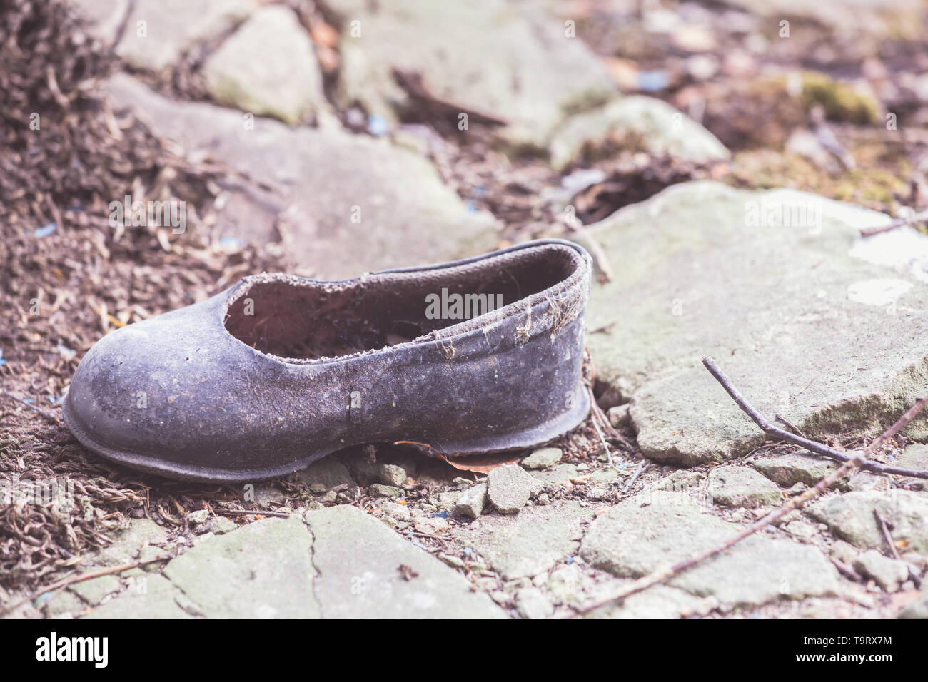 Abandoned little child shoe covered with dust in front of a collapsed ...