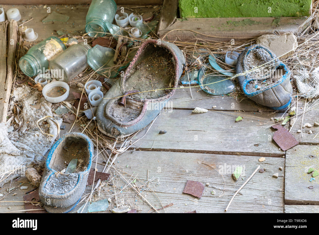 Abandoned shoes and bottles covered with dust in a collapsed house in ...