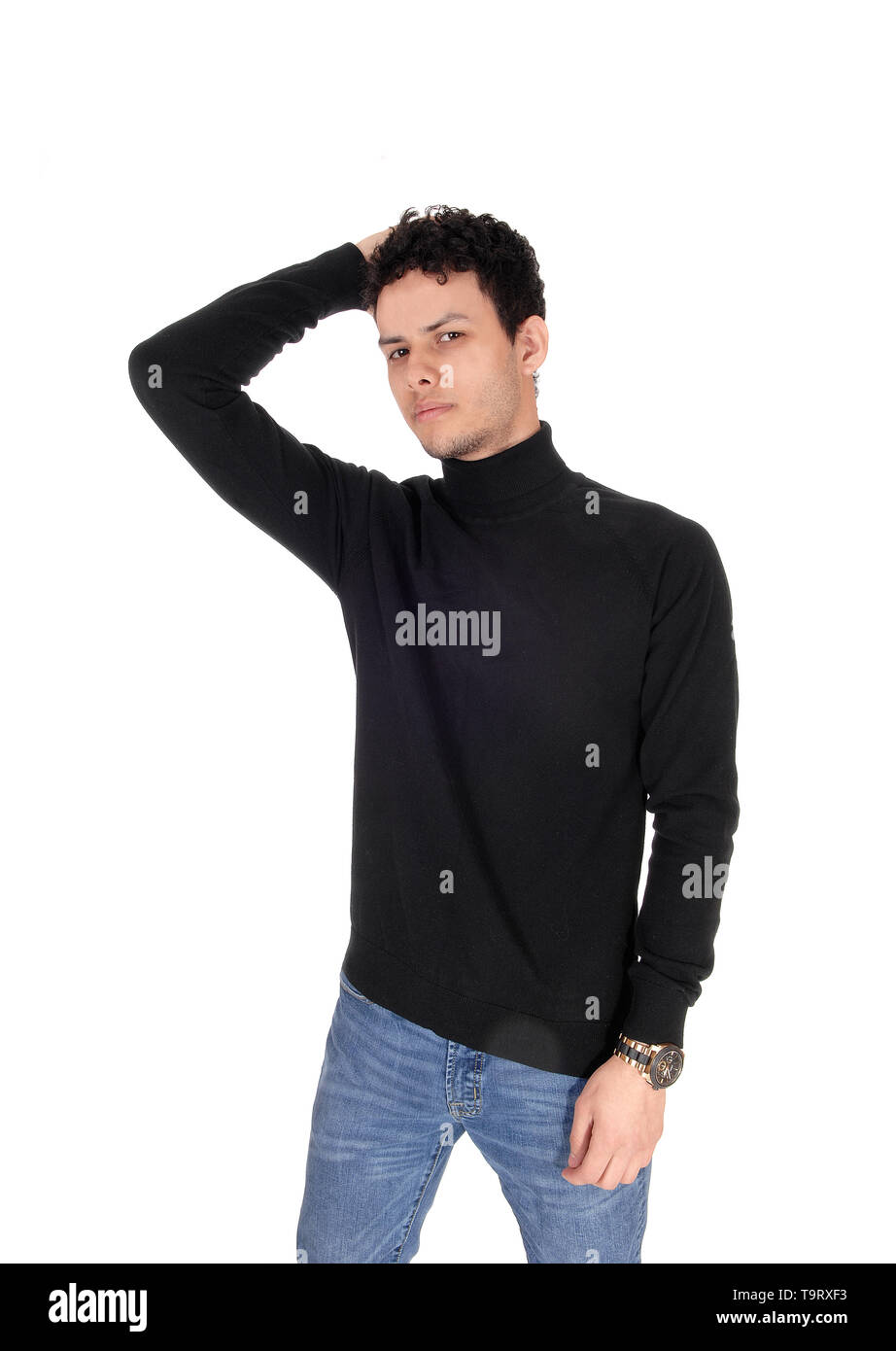 A slim young man standing in the studio with one hand on his head in a ...