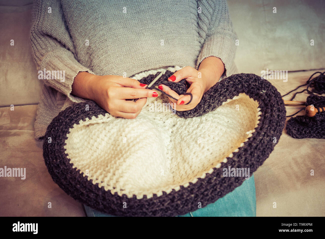 Girl making a crochet puff with white and gray wool and nails painted ...