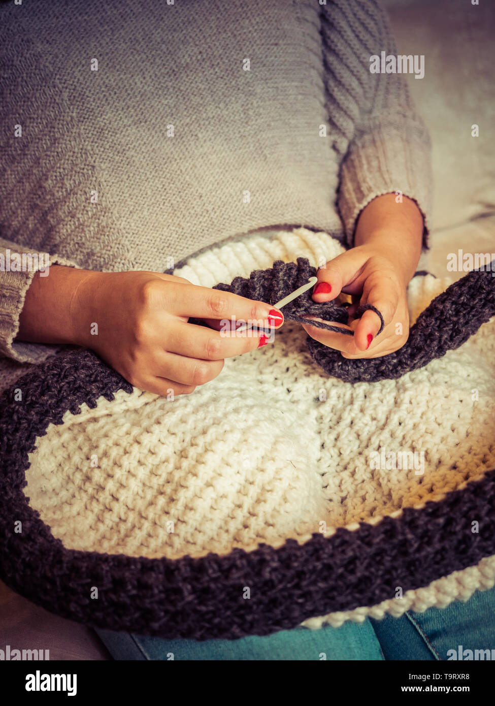 Girl making a crochet puff with white and gray wool and nails painted ...