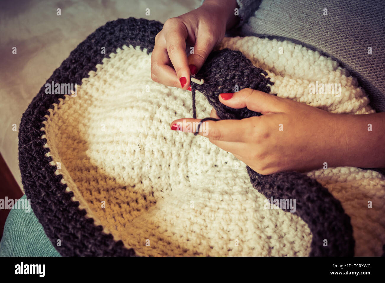 Girl making a crochet puff with white and gray wool and nails painted ...