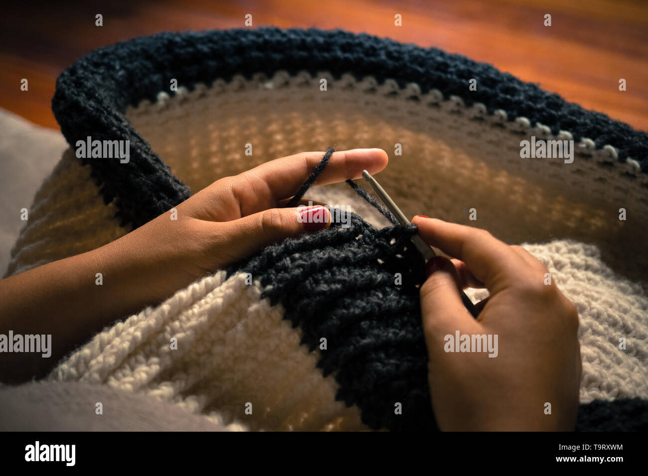 Girl making a crochet puff with white and gray wool and nails painted ...
