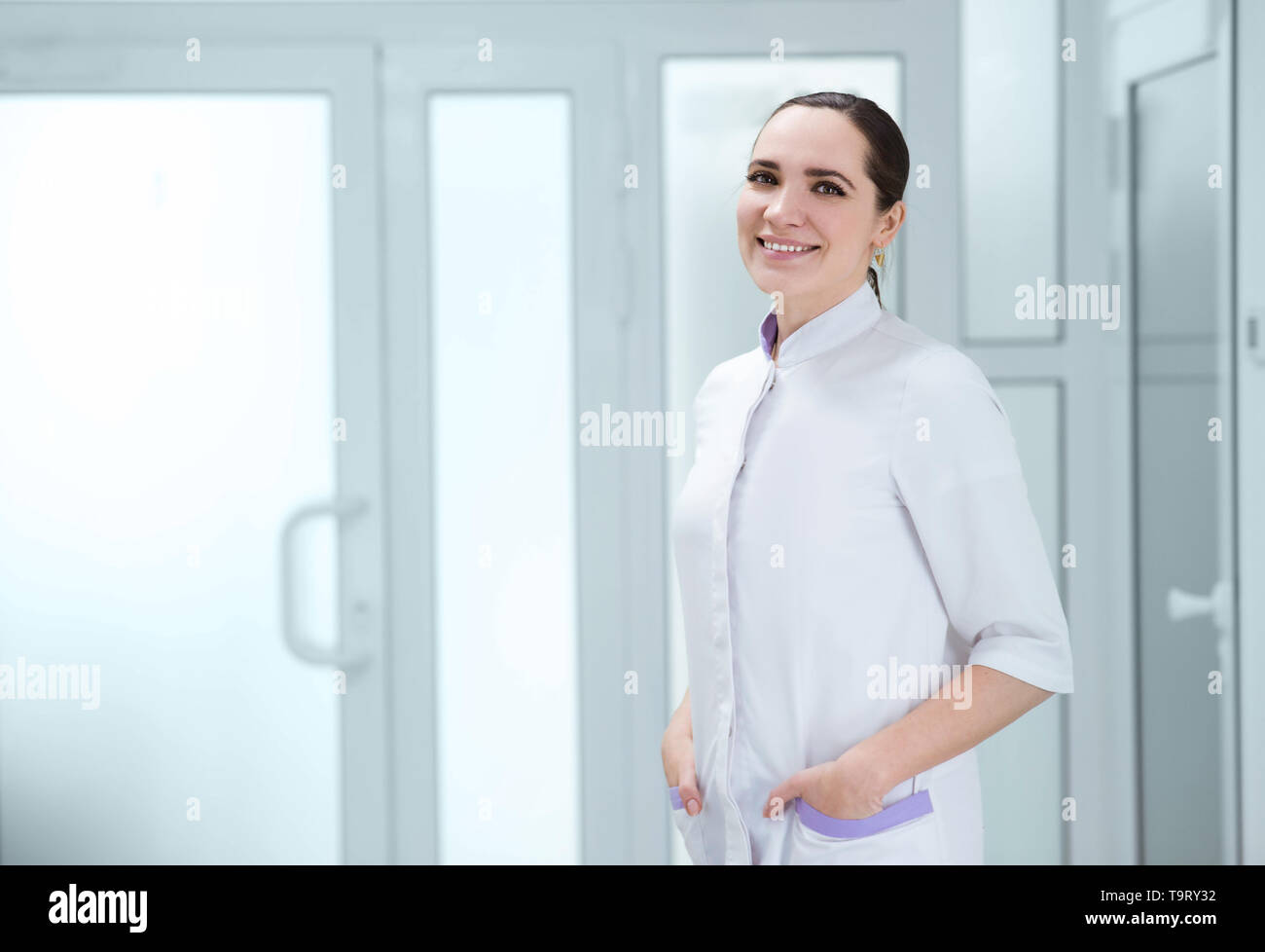 Portrait smiling doctor, standing at hospital corridor Stock Photo - Alamy