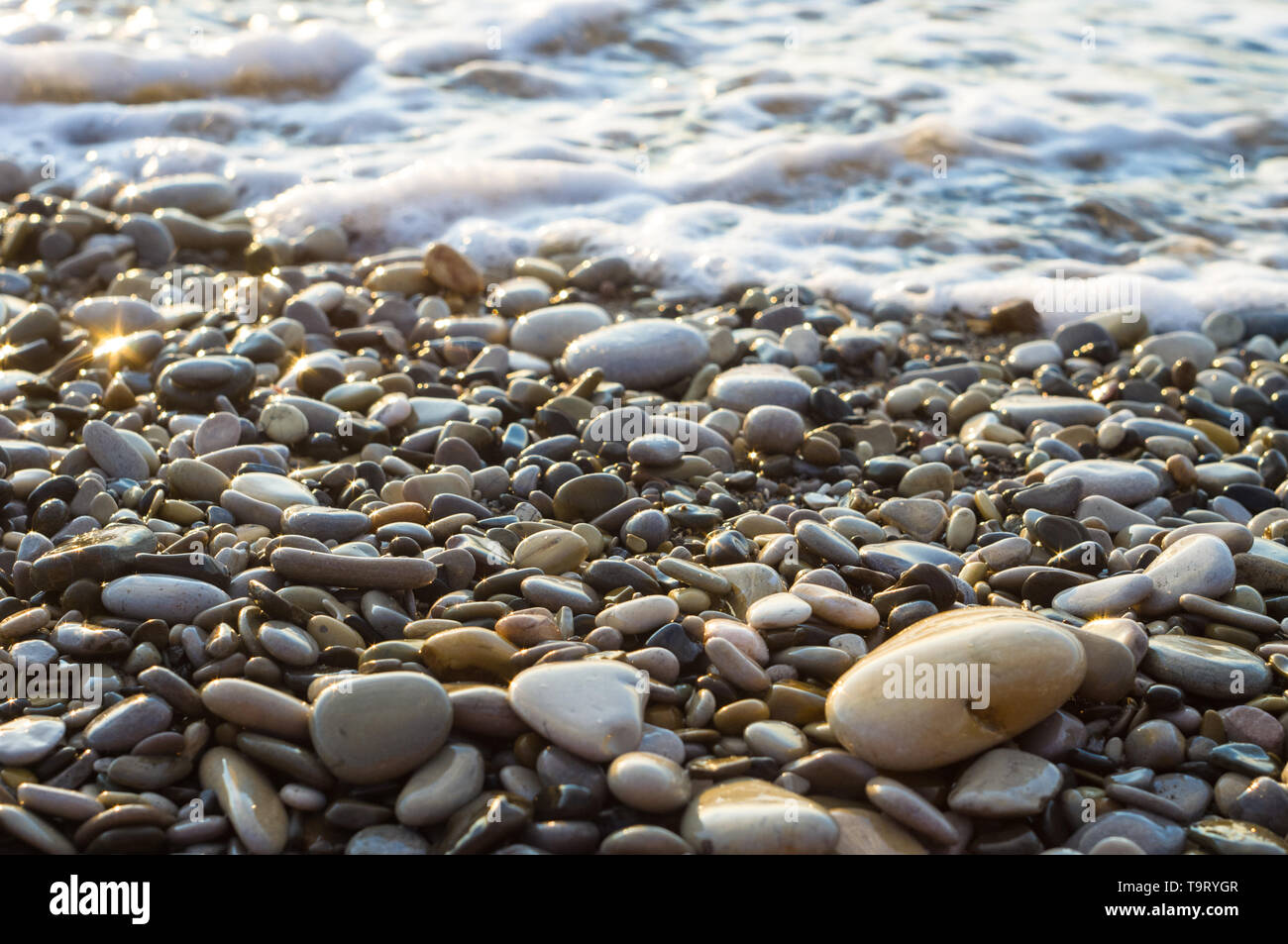 pebble stones on the sea beach on a warm summer day, the rolling waves ...