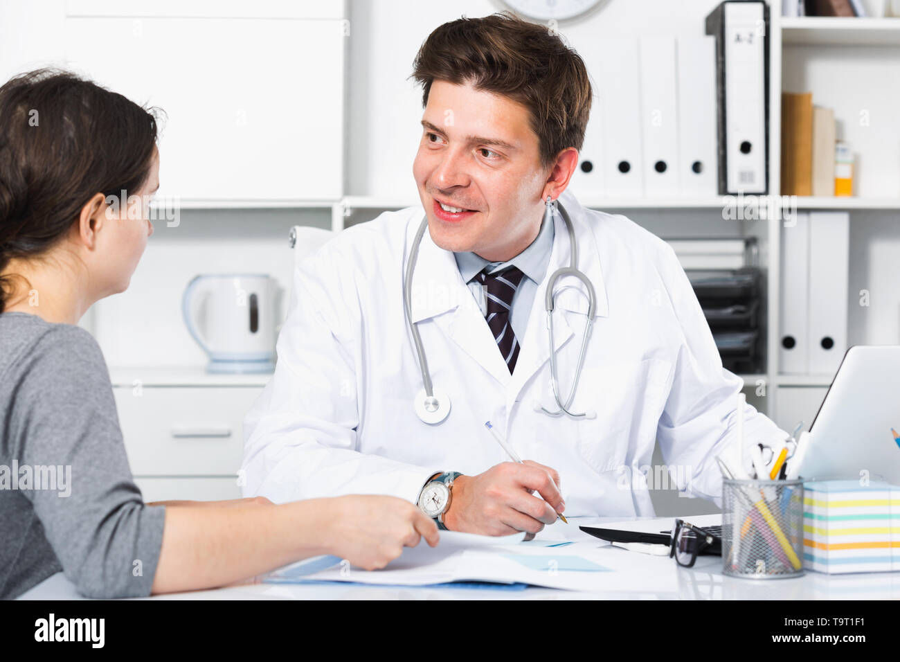Happy positive doctor speaking with client in the medical center Stock ...