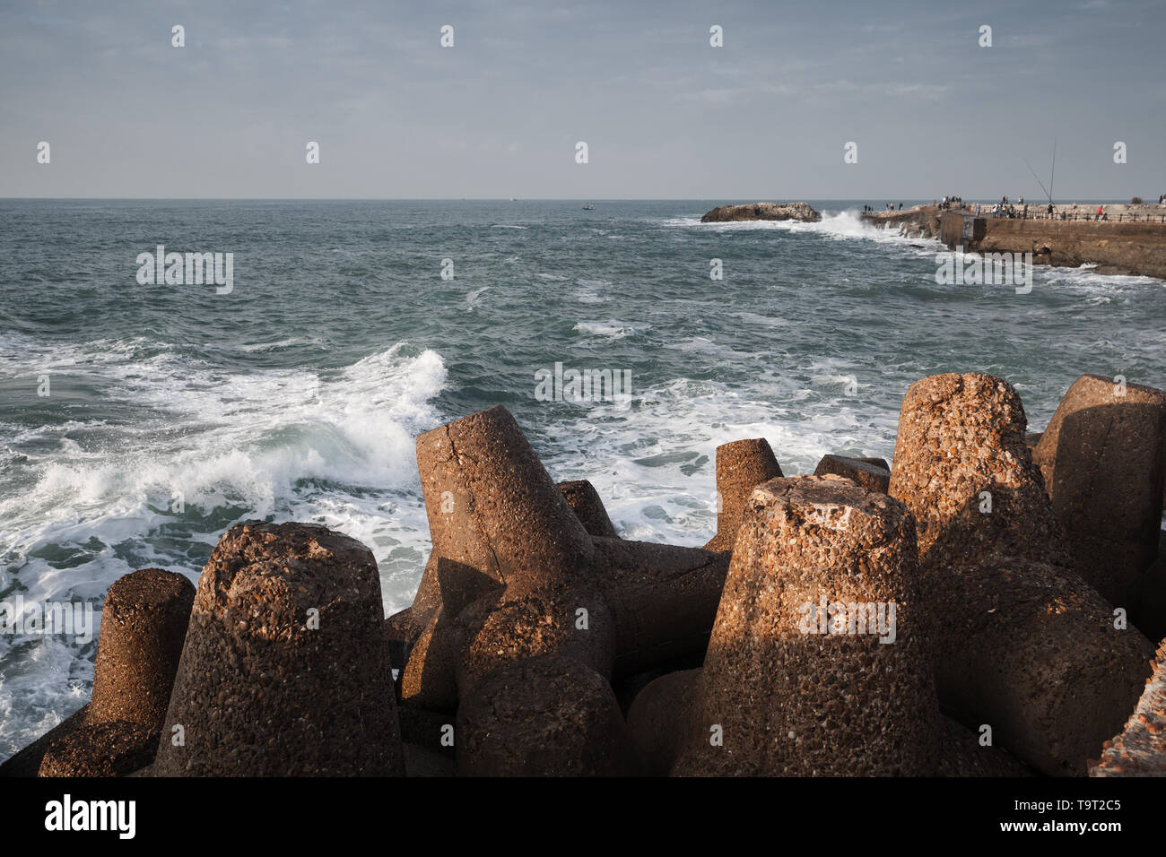 Dark breakwater blocks made of concrete with stormy seawater on a ...
