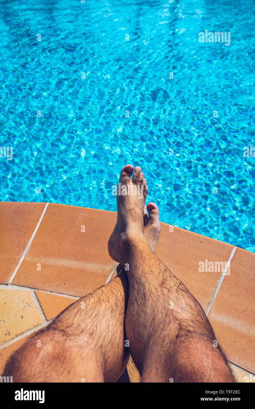 Relaxing at the swimming pool. Man relaxing next to swimming pool. Man ...