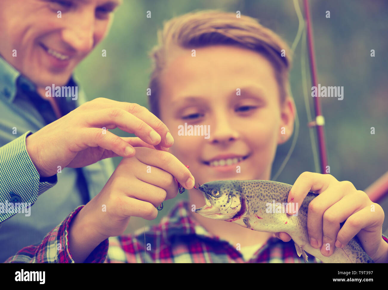Glad teenager boy holding and looking at a fish on hook Stock Photo - Alamy