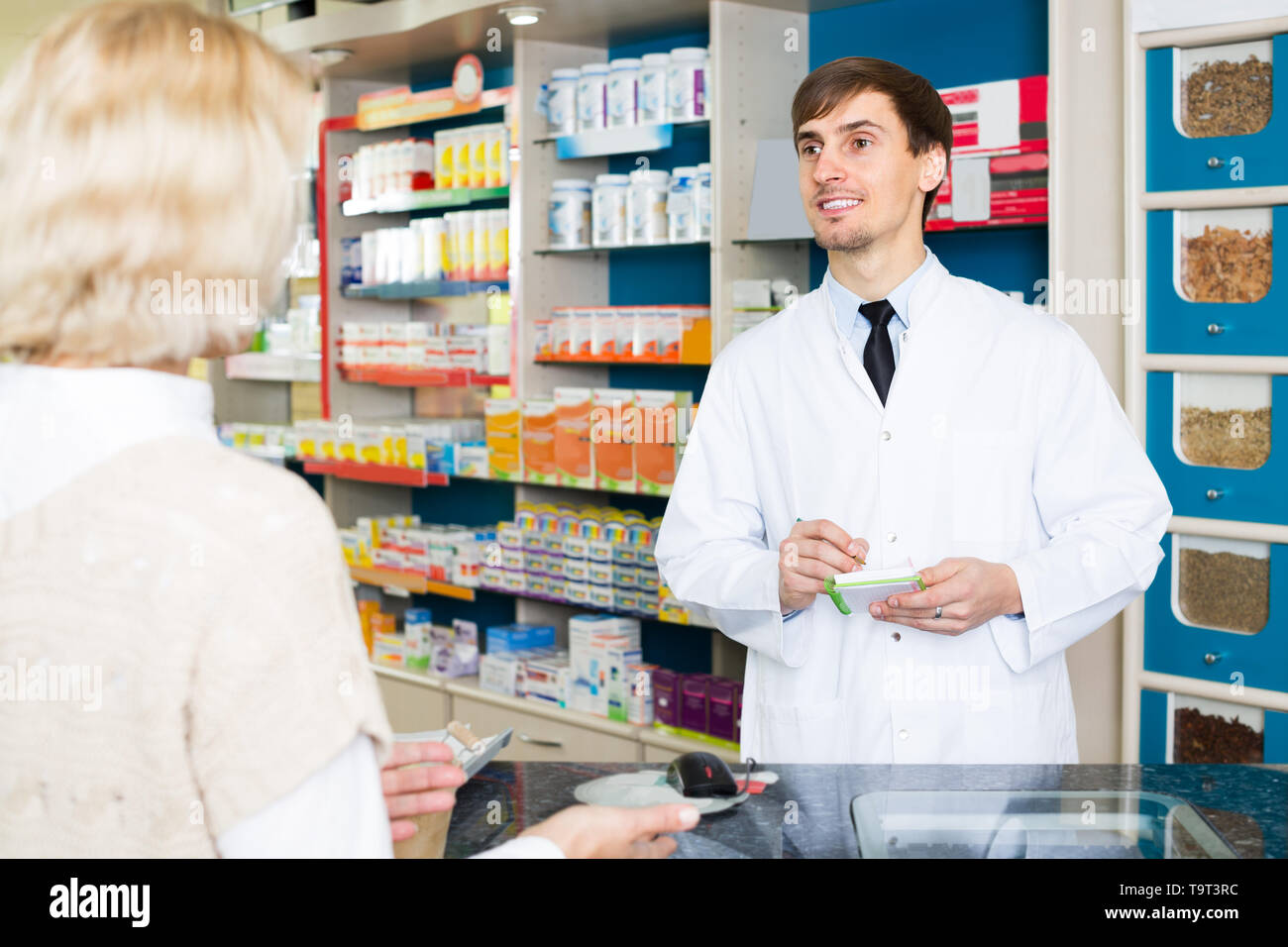 Professional pharmaceutist in drugstore helping girl to choose ...