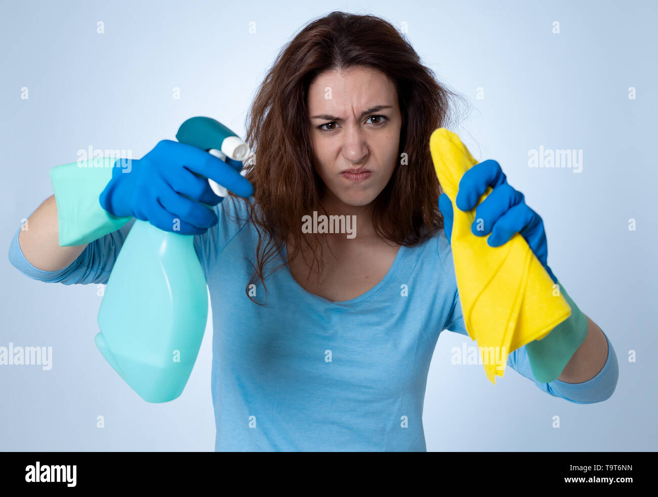 Angry and upset woman with cleaning spray and cloth cleaning feeling ...