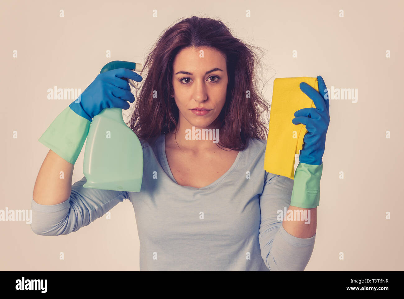 Beautiful angry and upset woman holding mop and cleaning spray feeling ...