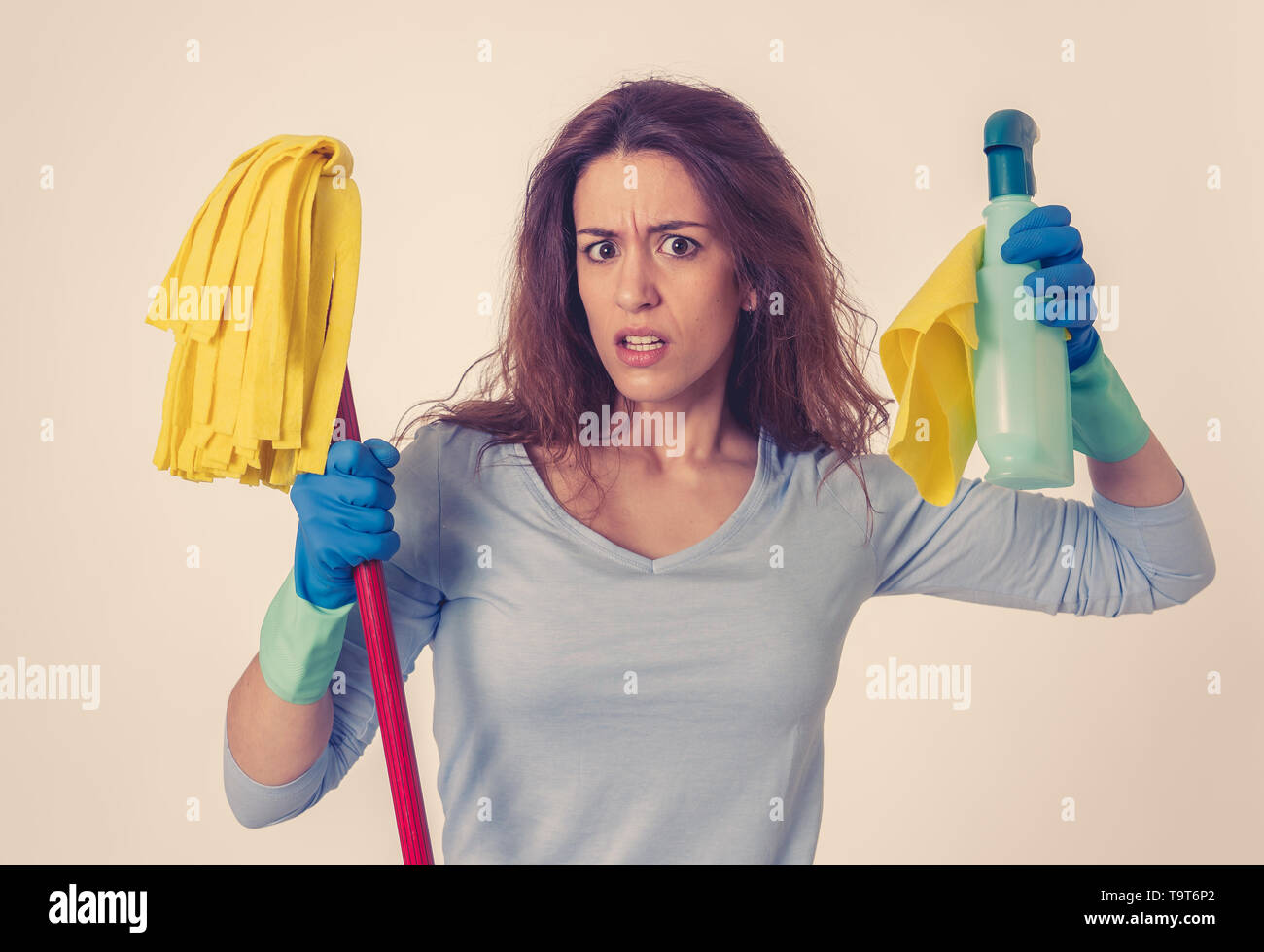 Beautiful angry and upset woman holding mop and cleaning spray feeling ...