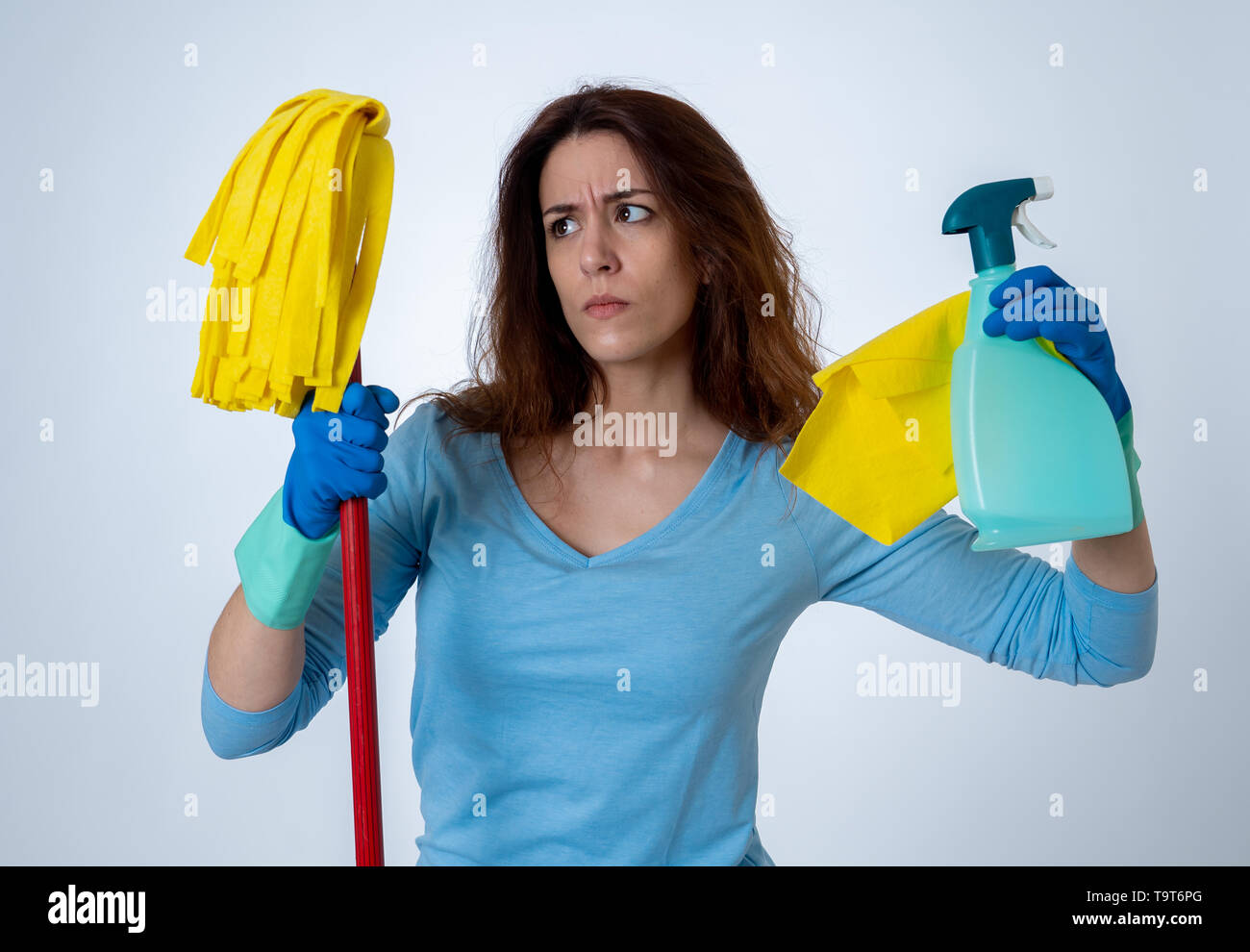 Beautiful angry and upset woman holding mop and cleaning spray feeling ...