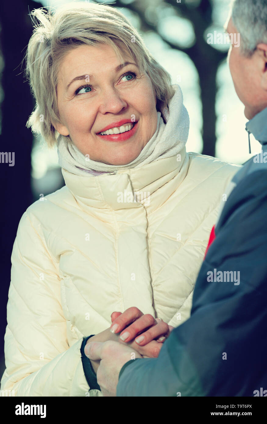 Husband and happy wife sitting on park bench and hold each other's ...