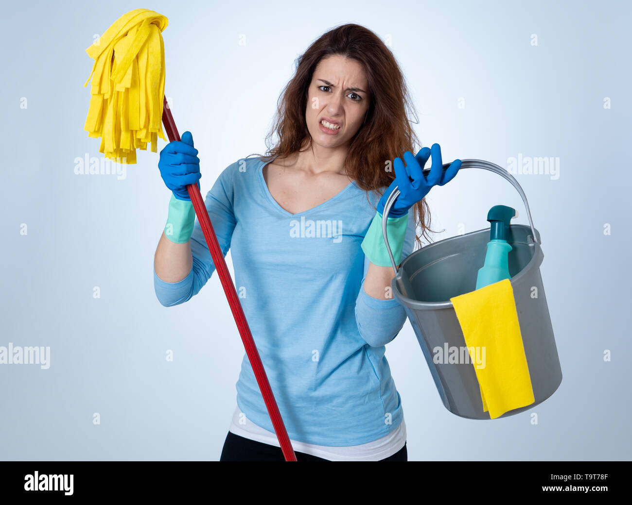 Beautiful angry and upset woman holding mop and cleaning spray feeling ...