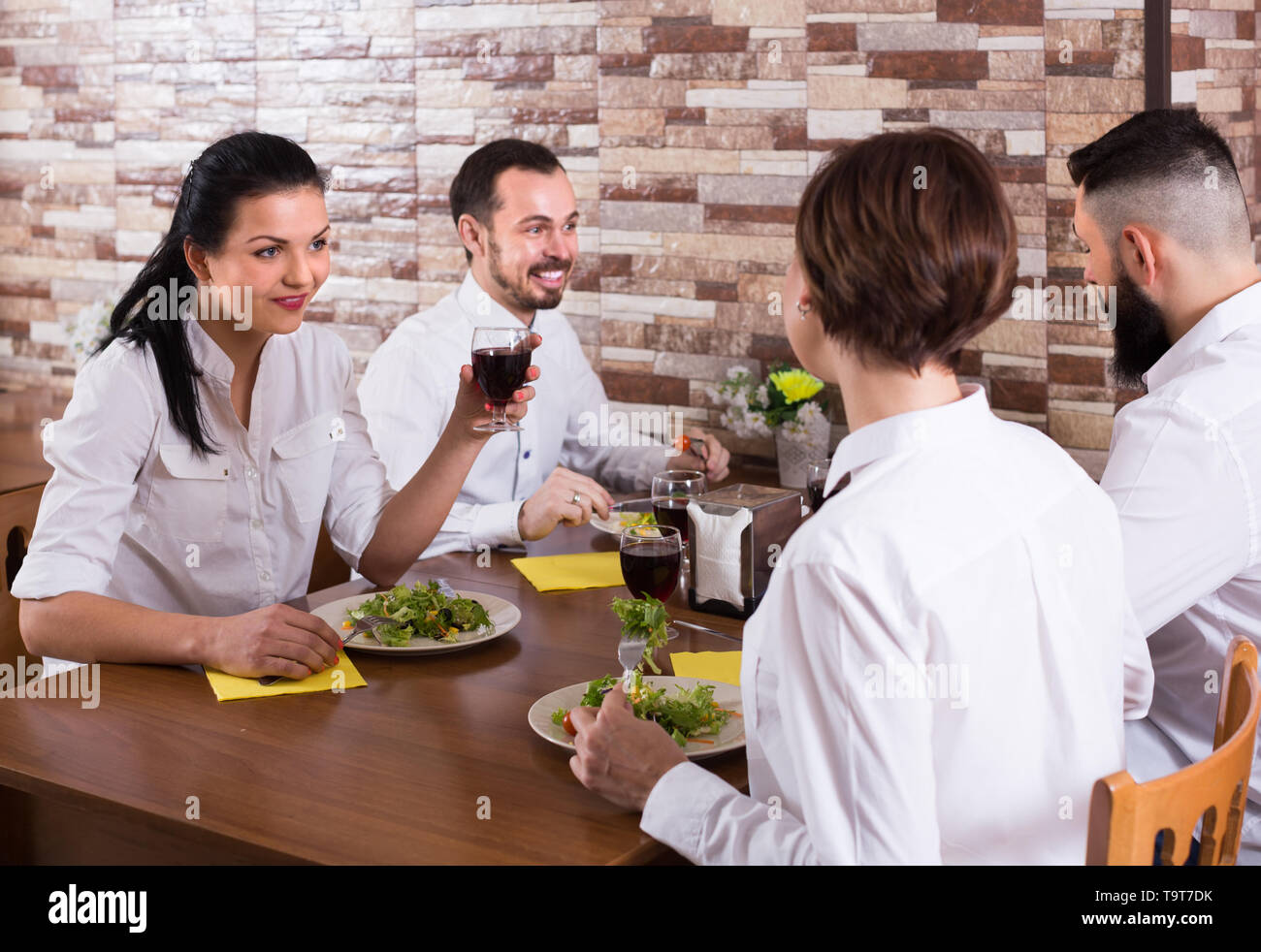 group of joyous friends eating at restaurant table and chatting Stock ...