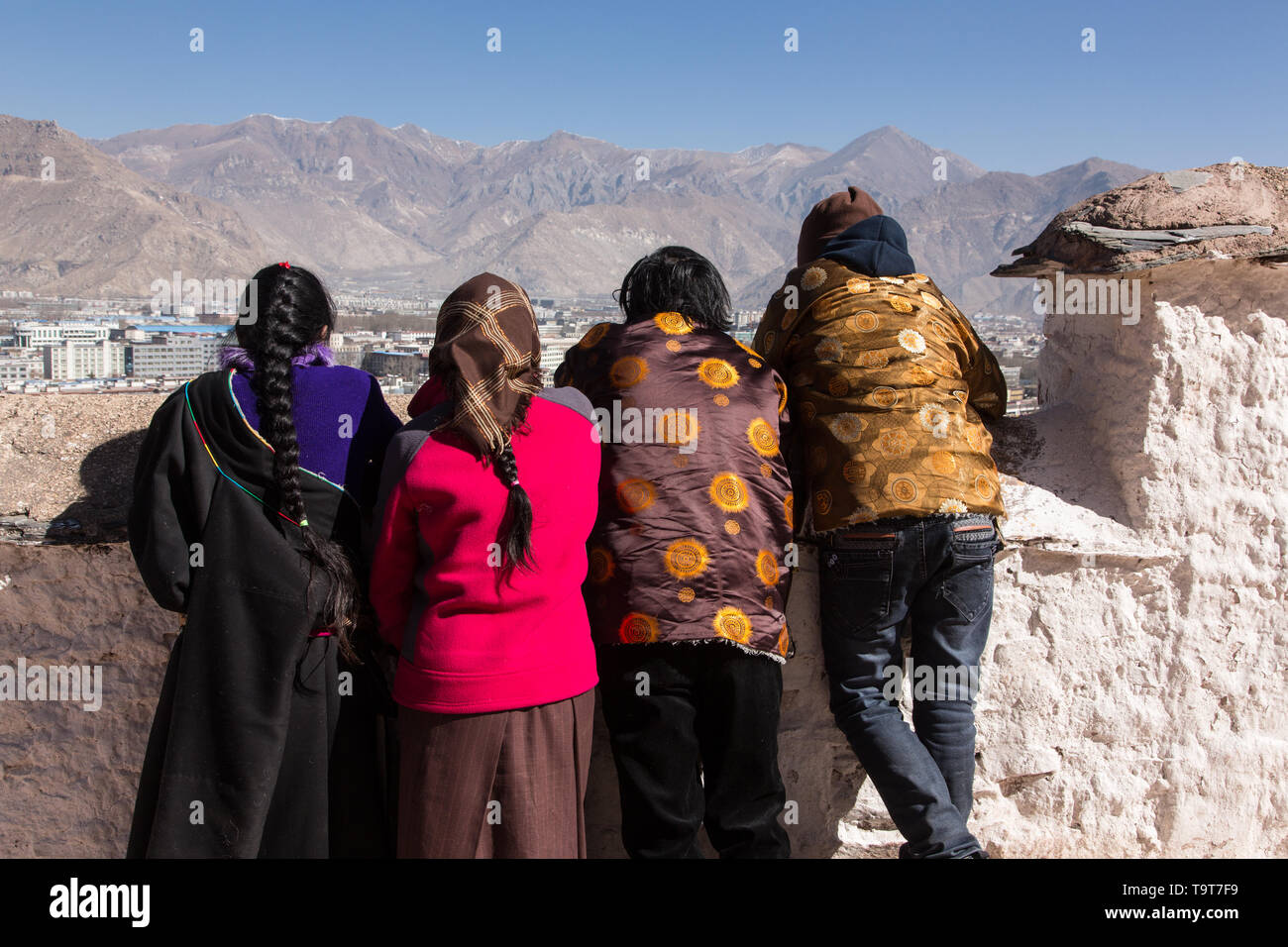 A family of Tibetan pilgrims visiting the Potala Palace look out over ...