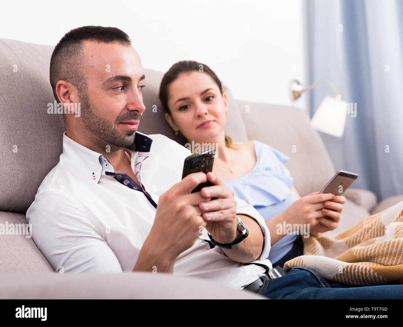 Couple is chatting on phone on the sofa at home Stock Photo - Alamy