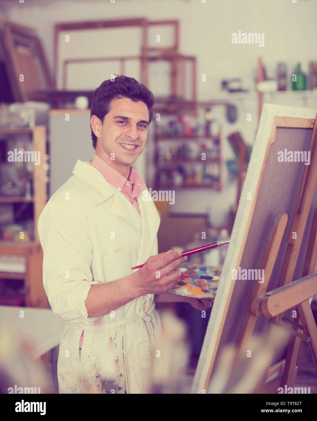 Creative male artist drawing picture with oil paints in studio Stock ...
